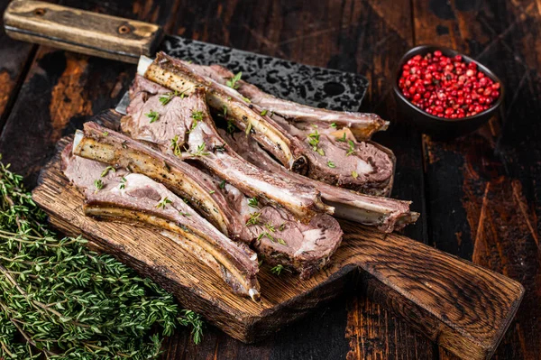 Grilled mutton Chops steaks on butcher board with meat cleaver. Dark ...