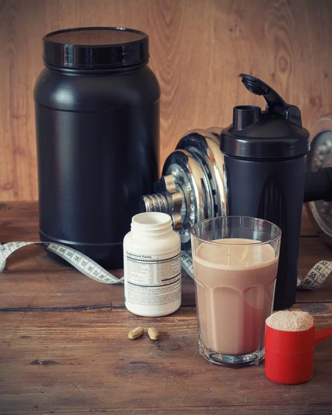 Whey protein powder in scoop and plastic shaker on wooden background ...