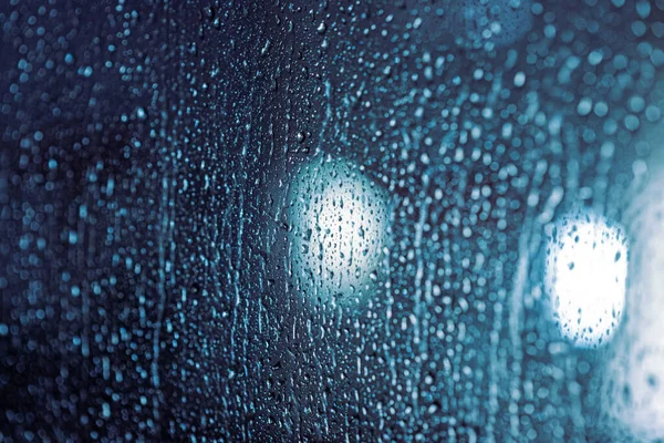 Close up of rain drops on the window in rainy night, cool lights ...