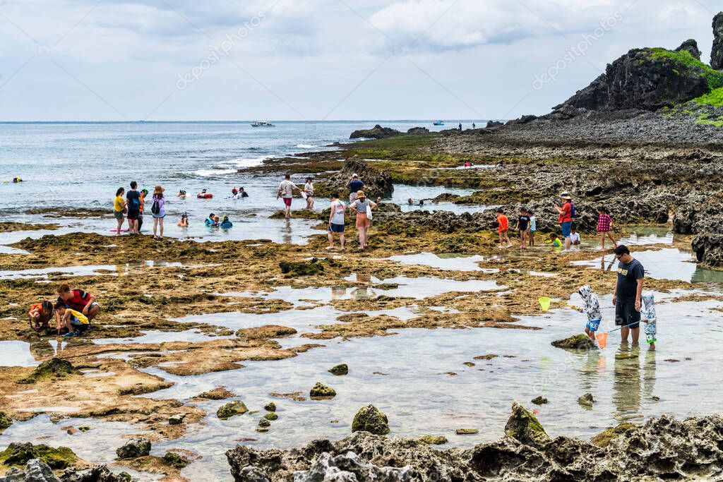 Los turistas exploran la zona intermareal a lo largo de la costa del Parque Nacional Kenting en ...