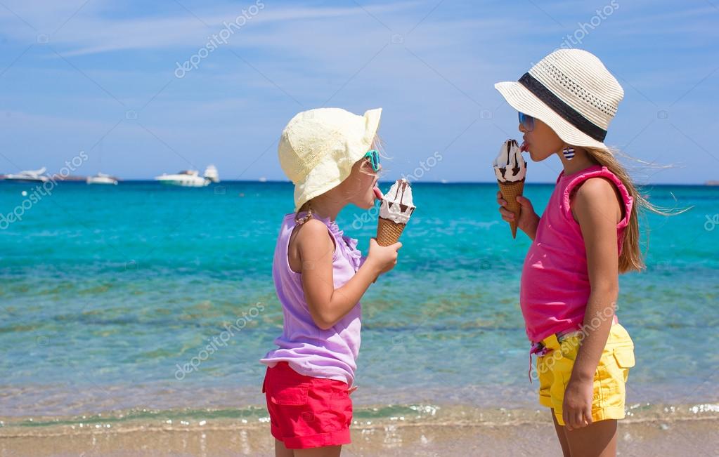 Little happy girls eating ice cream on tropical beach — Stock Photo © d ...