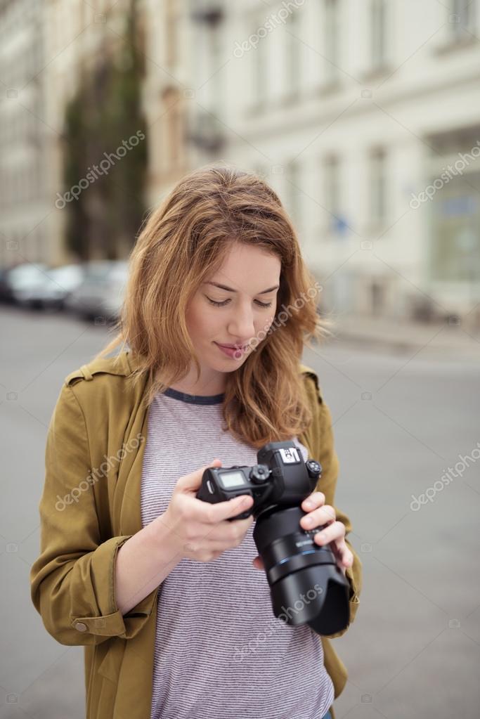 Pretty young photographer checking an image — Stock Photo © racorn ...