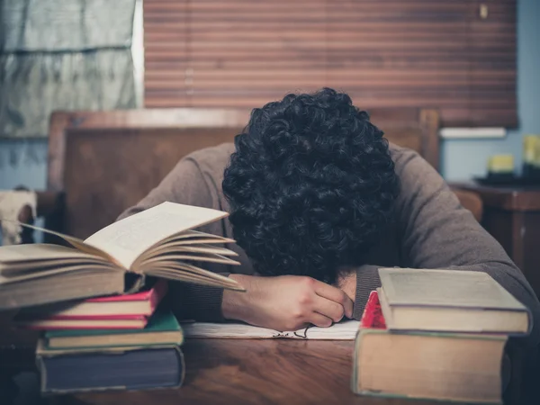 Tired student surrounded by books - Stock Image - Everypixel