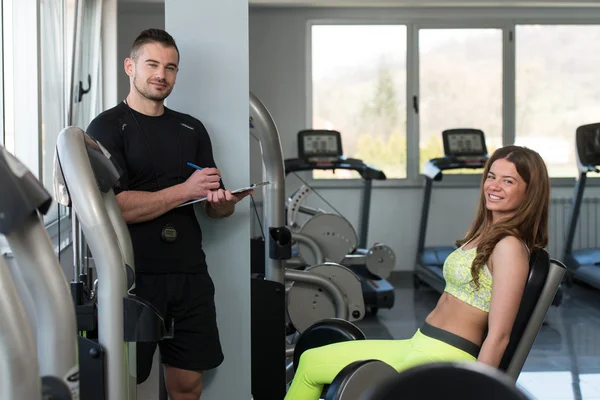 Personal Trainer Takes Notes While Woman Exercising Legs - Stock Image ...