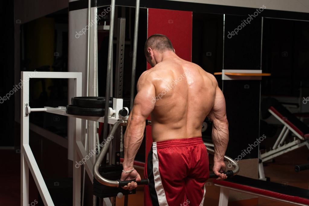Joven macho haciendo ejercicios de trapecio en el gimnasio 2022