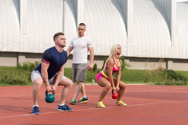 Two People Doing Kettlebell Exercise Outdoor With Instructor - Stock ...