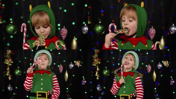 Kid girl in Christmas elf Santa Claus helper costume licking candy cane ...