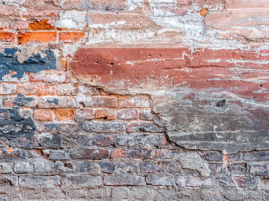 El viejo estuco de color dañado mecánicamente se derrumba de una pared ...