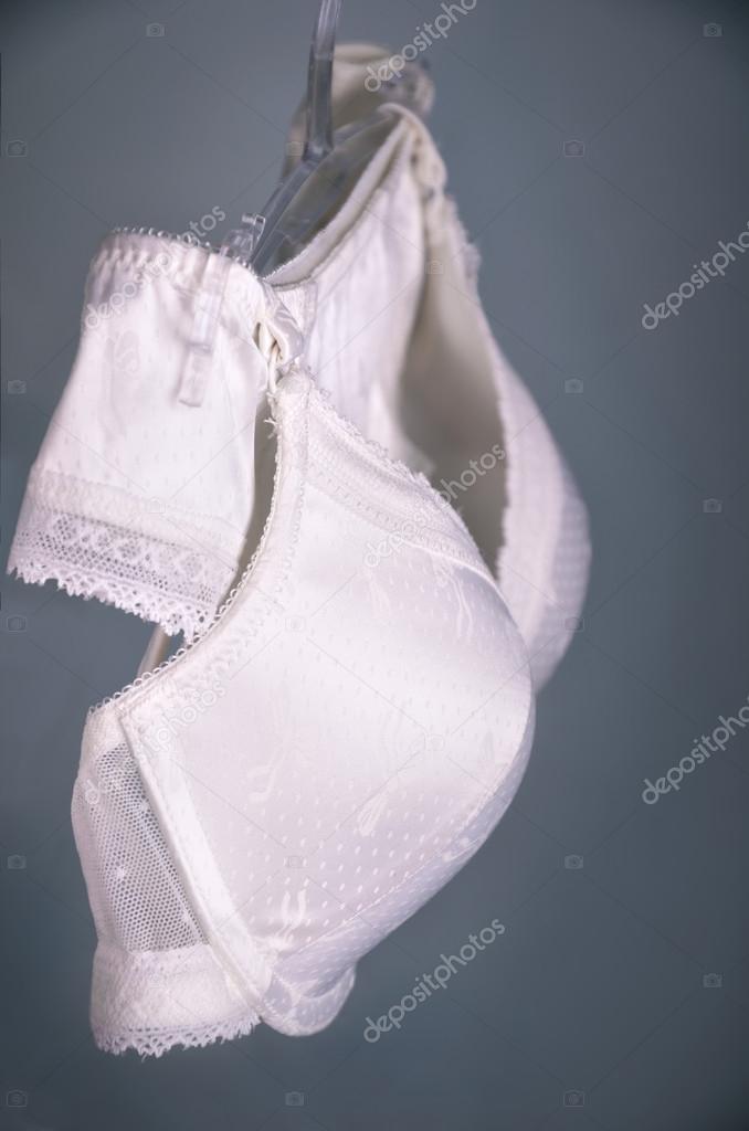 White lace lingerie hanging on the hanger on the gray-blue backg ...