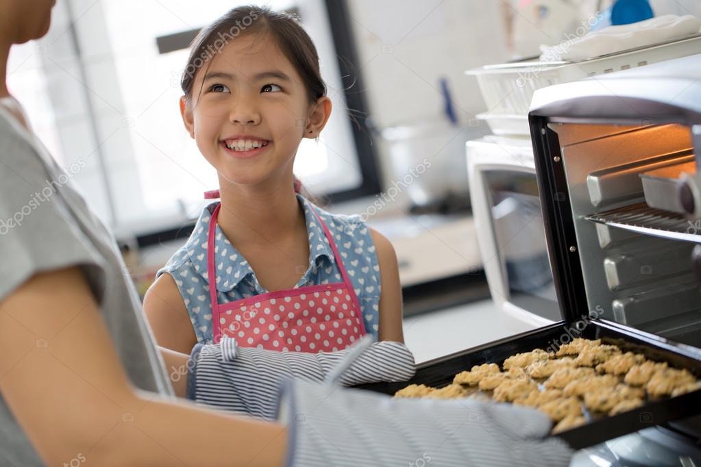 Happy little Asian cute chef looking cookies from oven — Stock Photo ...
