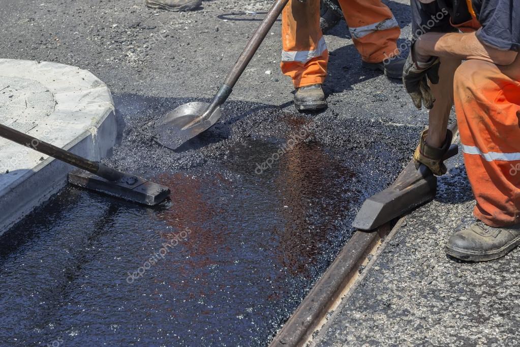 Trabajadores que utilizan una herramienta de asfalto para extender el ...
