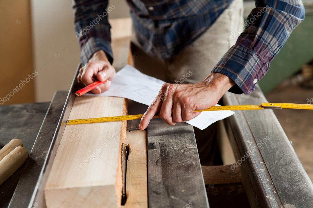 Carpenter measuring a plank — Stock Photo © Implementar #82583828