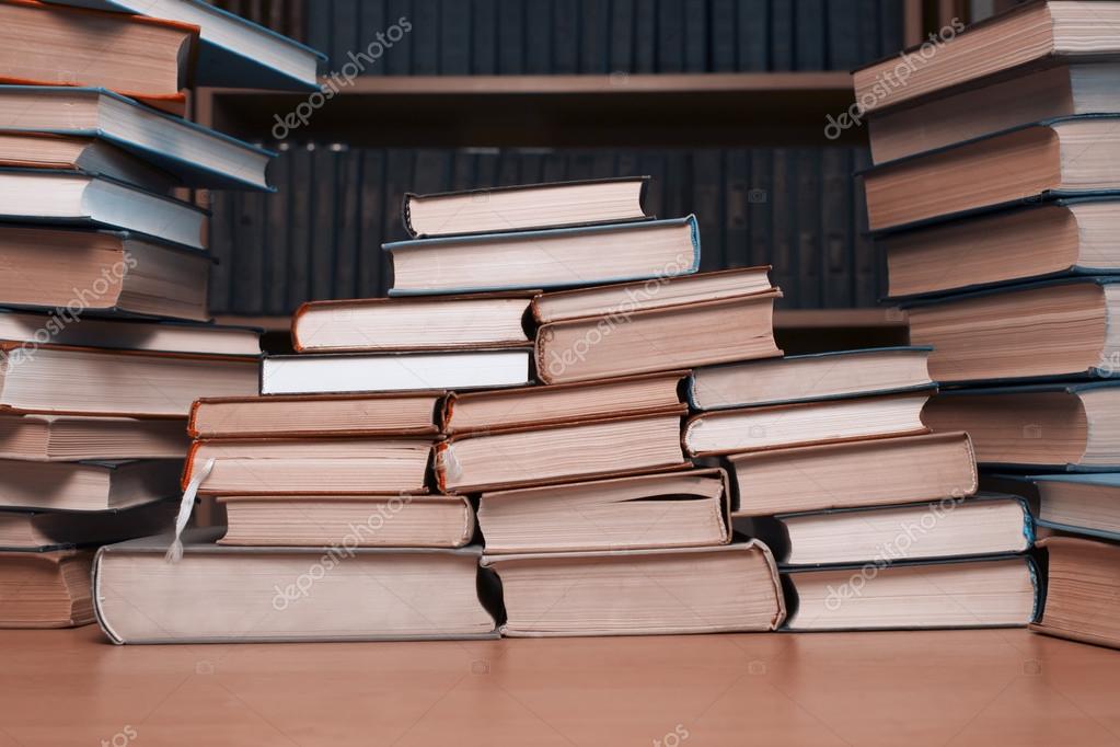 A pyramid of books on the table-background of bookshelves Stock Photo ...