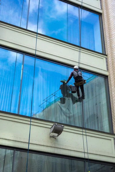 Window cleaner hanging on rope at work on skyscraper — Stock Photo ...
