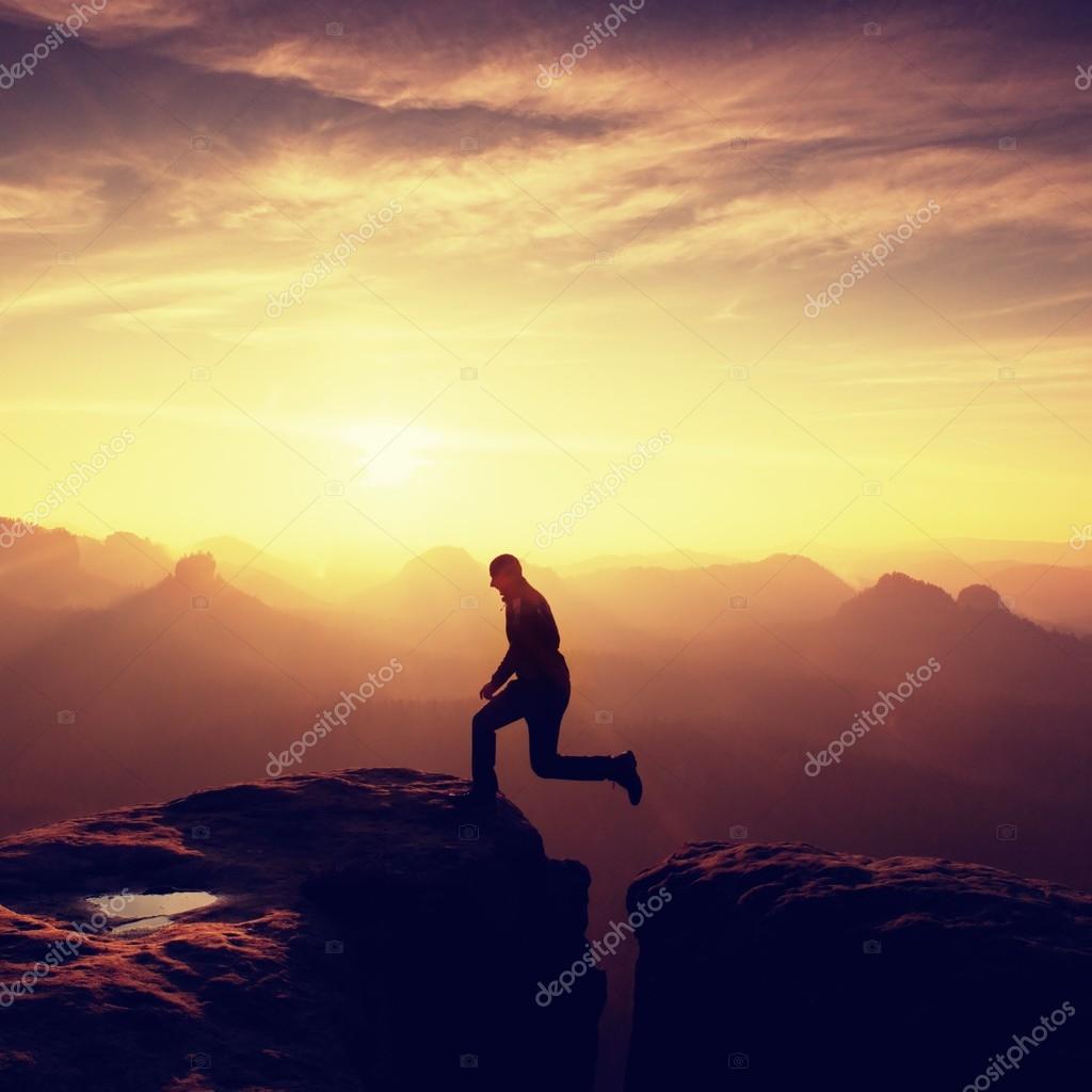 Happy man jumping between rocks, misty mountains. Stock Photo by ...