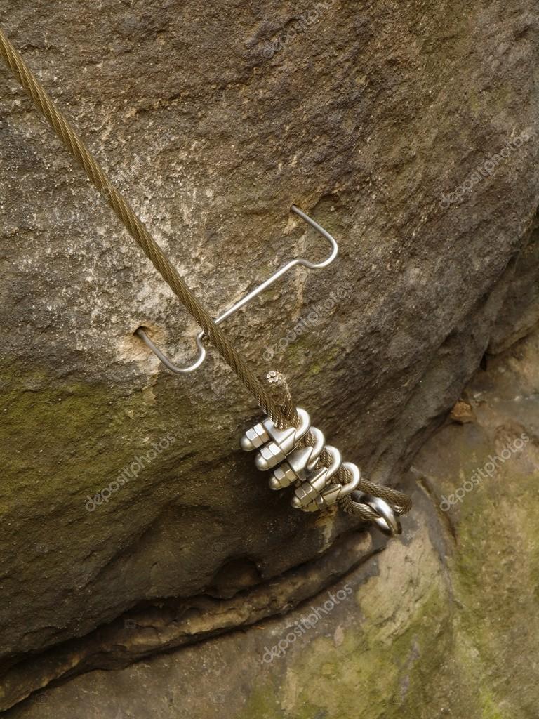 Detail of rope end of ferrata way anchored into sandstone rock. Iron ...