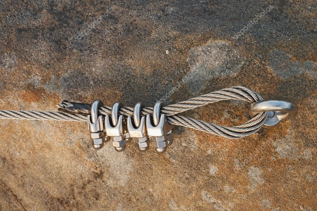 Solid knot on steel rope. Iron twisted rope fixed in block by screws ...