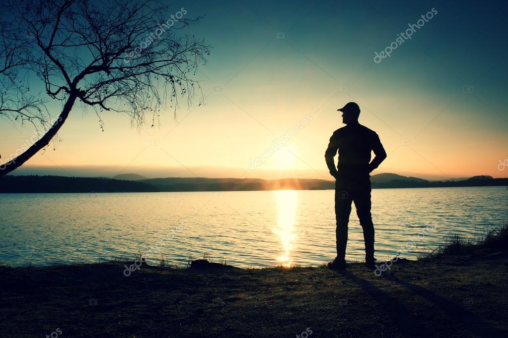 Silhouette of young man stand on beach at sunset. Shadow of active man ...