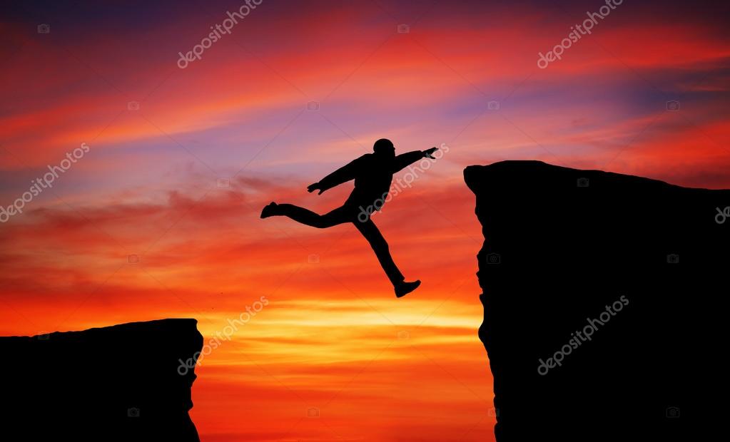 Man jumping across the gap from one rock to cling to the other. Stock ...
