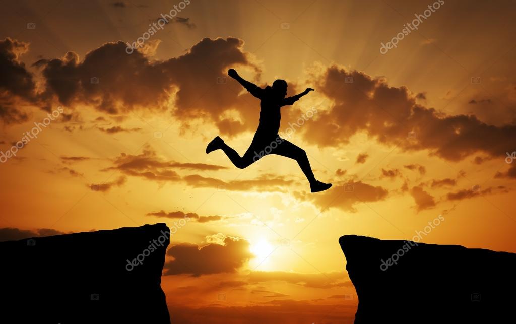 Man jumping across the gap from one rock to cling to the other. — Stock ...