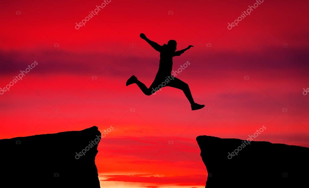 Man jumping across the gap from one rock to cling to the other. Stock ...