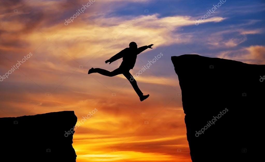 Man jumping across the gap from one rock to cling to the other. Stock ...