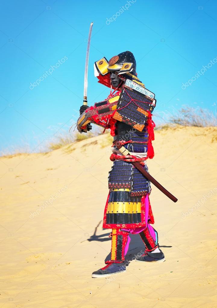 Hombre con traje de samurai con espada corriendo sobre la arena. 2022