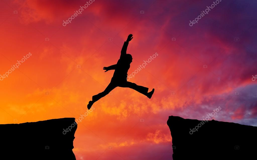 Man jumping across the gap from one rock to cling to the other. Stock ...