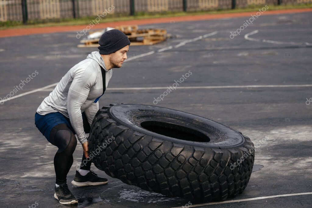 Un hombre fuerte, grande y fornido levanta una rueda. el concepto de un ...