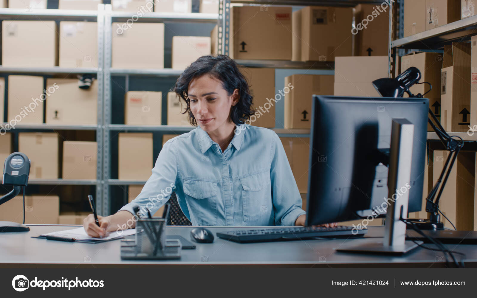 Female Inventory Manager Works on a Computer while Sitting at Her Desk ...