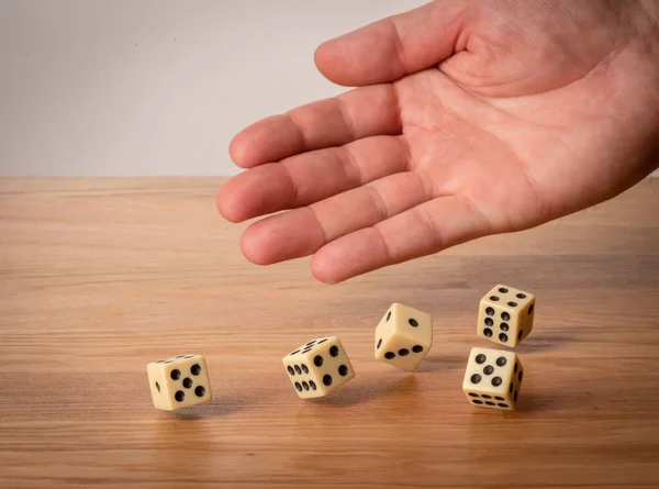 Hand Rolling Dice On Table