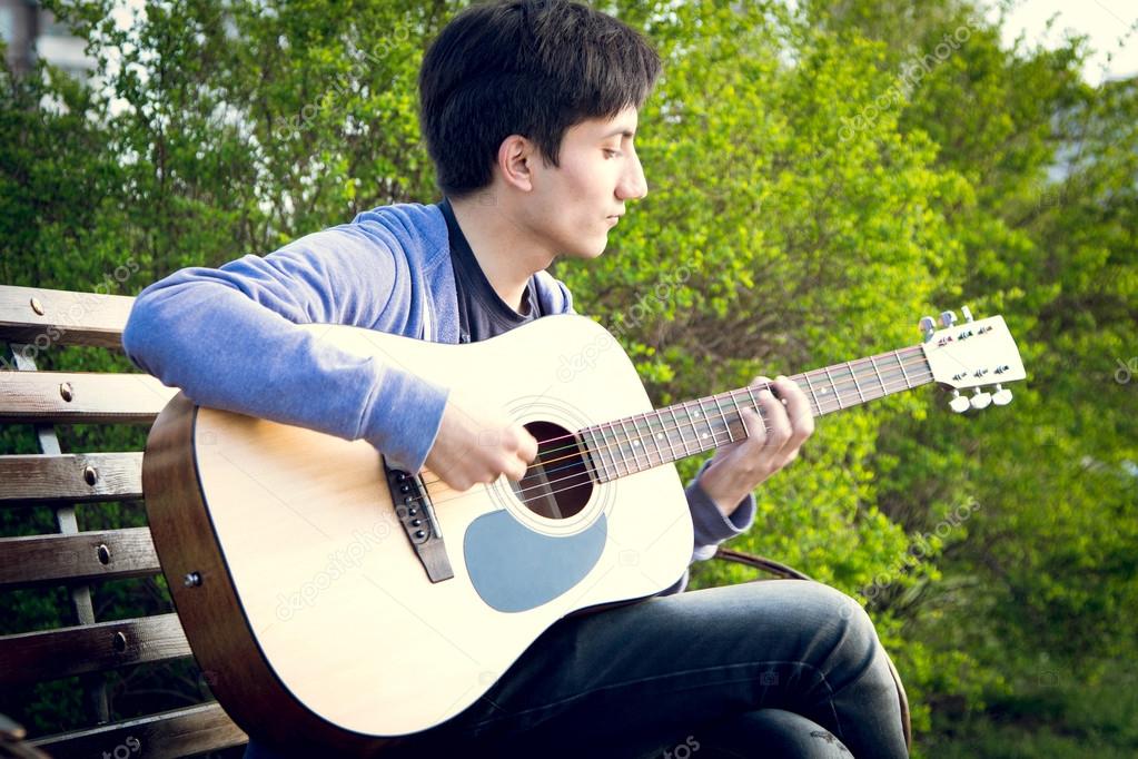 Young guy playing guitar in the park — Stock Photo © fantom_rd #70897695