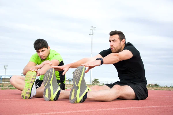 Men stretching in running track - Stock Image - Everypixel