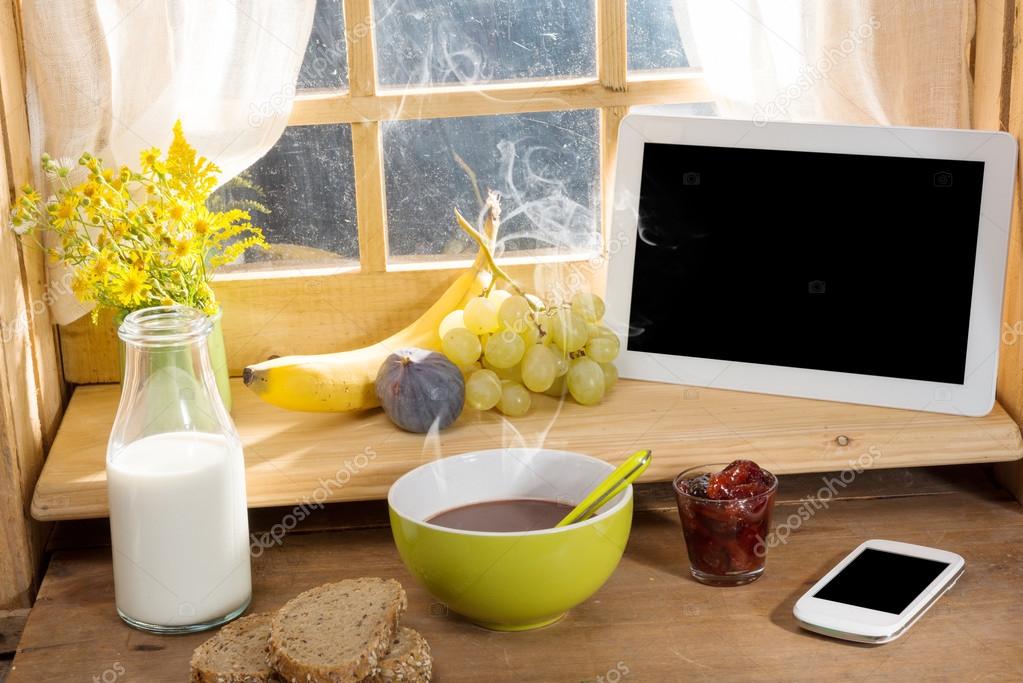 Breakfast with milk, bread, tablet and phone, on the edge of a w Stock ...