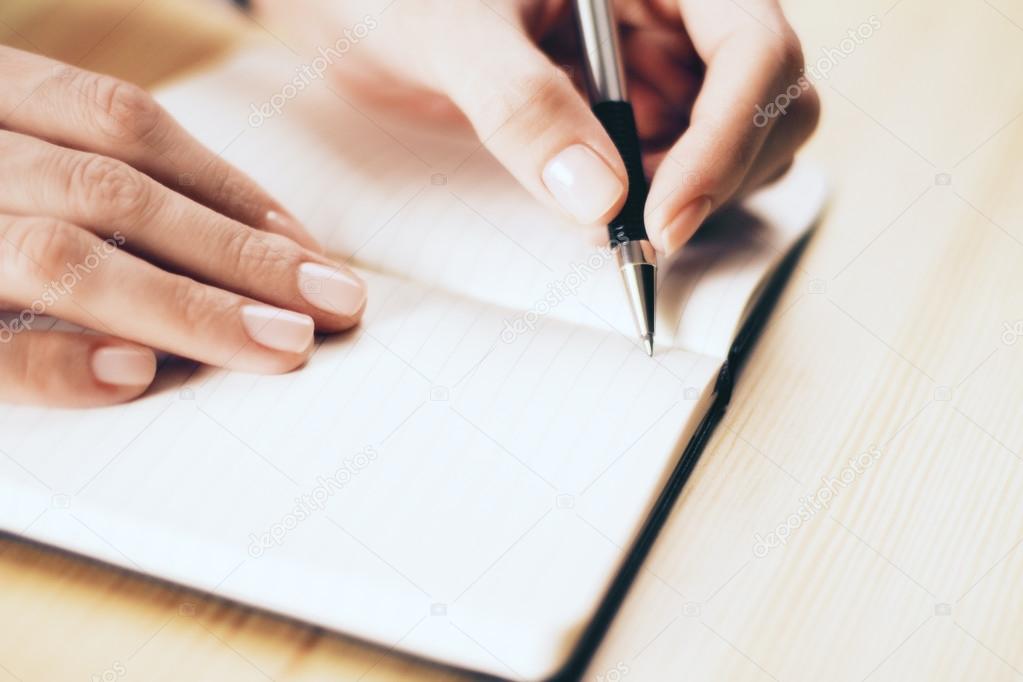 Female hands writing in notebook with pen on wooden table — Stock Photo ...