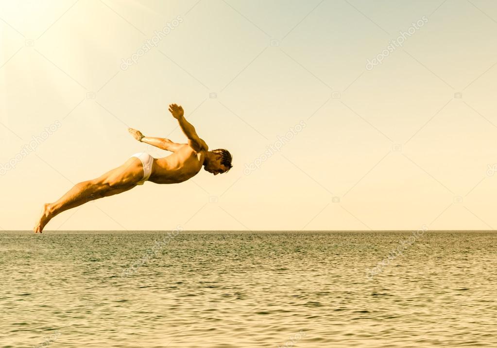 Cliff diver jumping in the sea against the sky at sunset - Concept of ...
