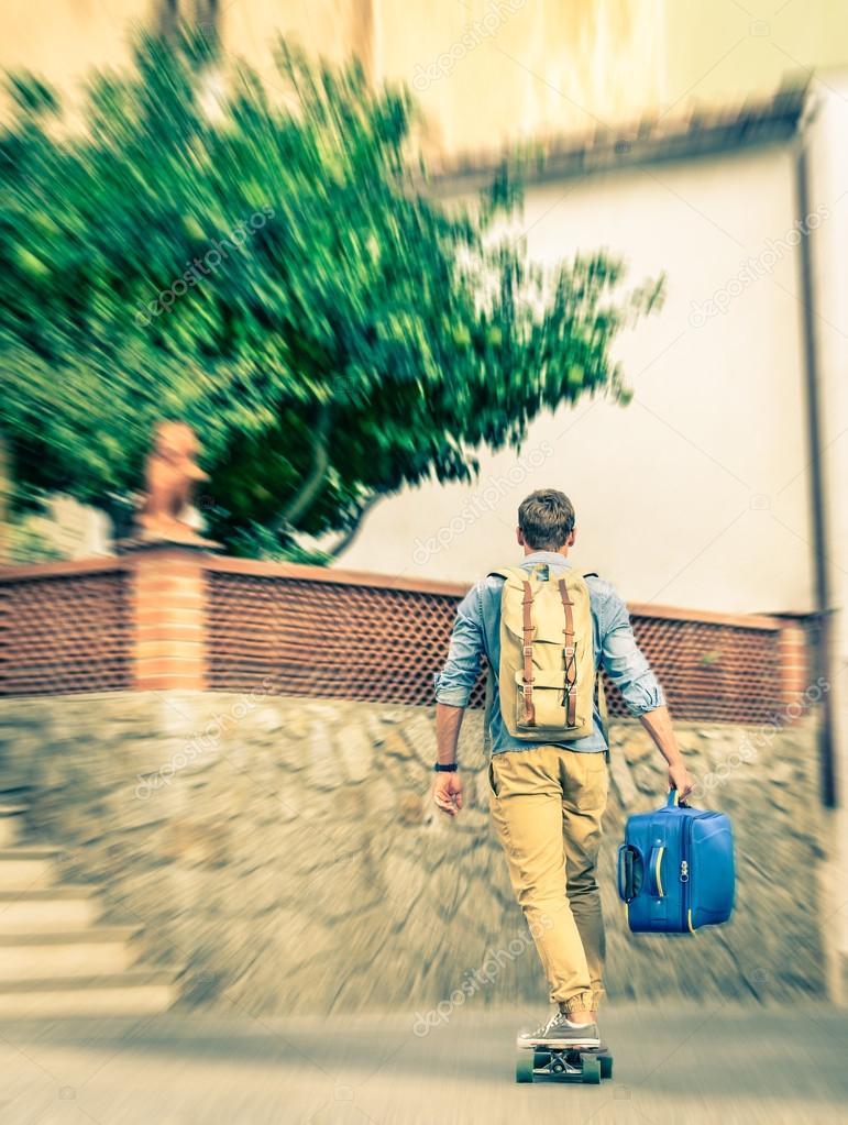 Joven hombre hipster avanzando con su longboard sosteniendo su mochila ...