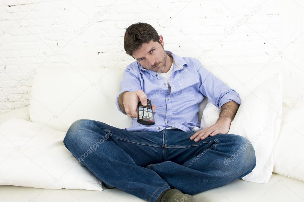 Man watching television at home living room sofa with remote control ...