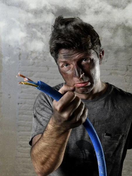 Young man holding cable smoking after electrical accident with dirty ...