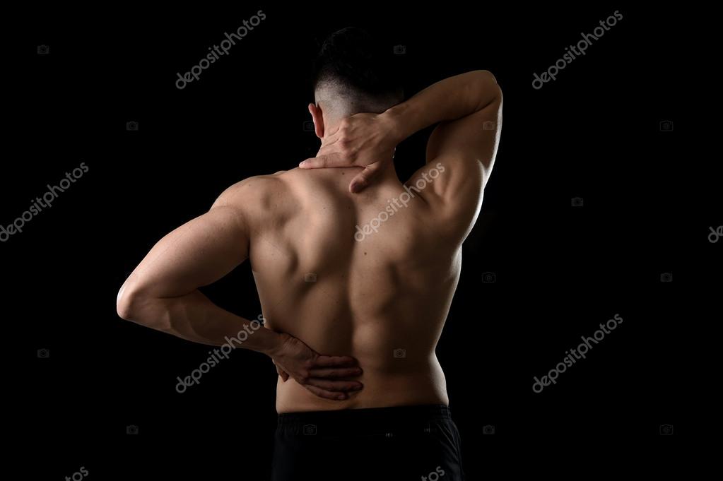 Back view of young man with muscular body holding his neck and low back ...