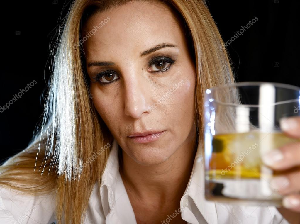 Drunk alcoholic woman alone in wasted depressed face holding scotch whiskey glass wasted and ...