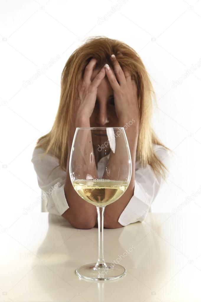 Caucasian blond wasted and depressed alcoholic woman drinking white wine glass desperate drunk ...