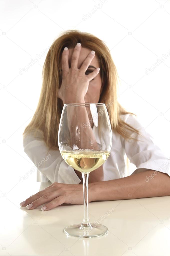 Caucasian blond wasted and depressed alcoholic woman drinking white wine glass desperate drunk ...