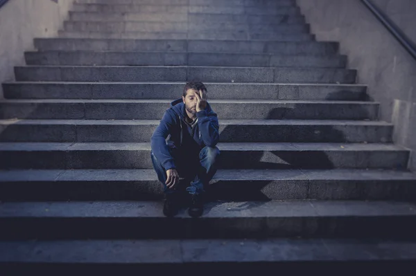 Young man lost in depression sitting on ground street concrete stairs ...
