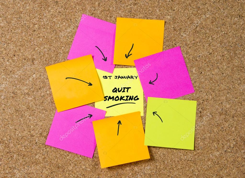 Yellow post it note on cork board and marker arrow as reminder of quit ...