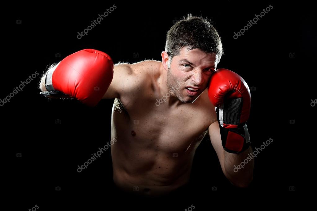 Furious man training boxing on gym with red fighting gloves throwing ...
