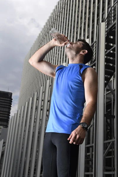 Young sport man drinking water bottle after running training session in ...