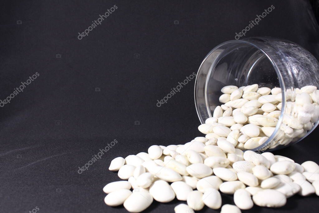 frijoles vertidos de un frasco de vidrio sobre el fondo negro de una ...