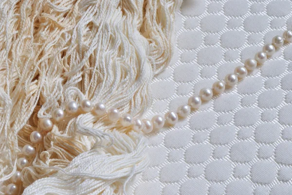 Photo of pearl string and threads on white textile textured background ...