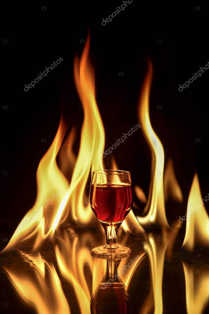 bebida roja con fuego detrás y reflexión sobre fondo negro. 2023